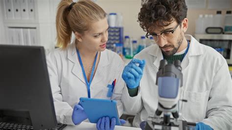 A Woman And Man Scientists Collaborating In A Laboratory Analyzing