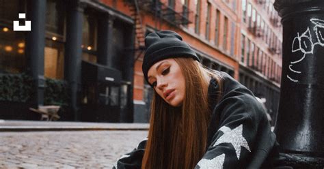 낮 동안 콘크리트 벤치에 앉아 있는 흑백 꽃무늬 긴 소매 셔츠를 입은 여자 사진 Unsplash의 무료 소호 뉴욕 Soho