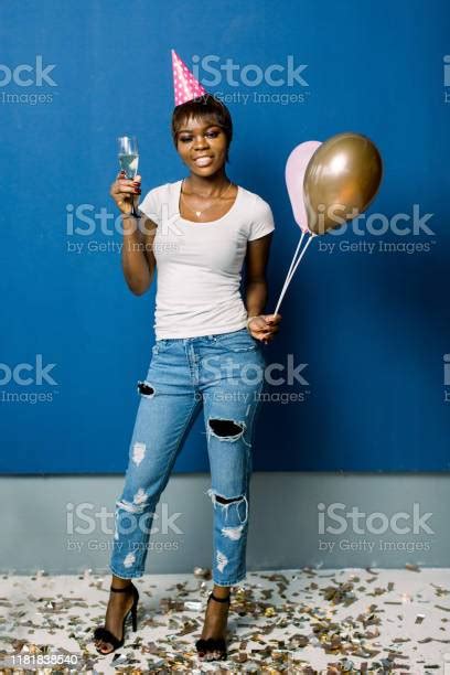 파란색 배경 위에 고립 된 풍선과 샴페인무리를 들고있는 쾌활한 젊은 아프리카 여성의 전체 길이 초상화 생일 파티 축 하 컨셉 감정에 대한 스톡 사진 및 기타 이미지 Istock