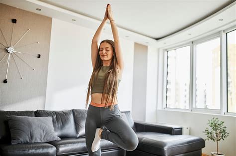 요가 컨셉을 연습하는 웃는 매력적인 여성 Vrksasana 운동에 서 나무 포즈 운동 스포츠웨어 검은 색 상단과 바지를 입고