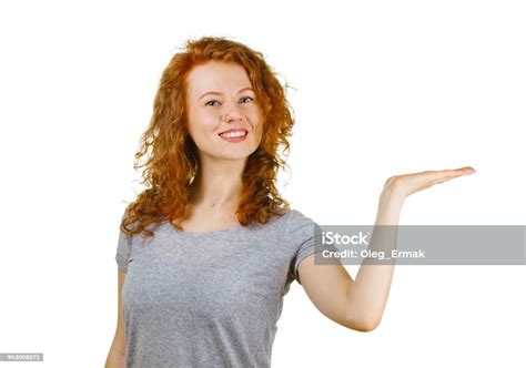 카메라를 보고 웃 고 회색 티셔츠에 곱슬 머리와 귀여운 빨간 머리 여자의 초상화 손 선물 또는 당신의 제품에 보여줍니다 흰색 배경에 고립 건강한 생활방식에 대한 스톡 사진