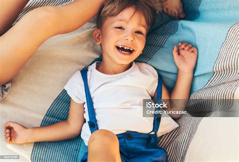 바깥 담요에 누워 웃고 있는 어린 소년의 머리 위 사진 공원에서 여름날을 즐기는 행복한 아이 잘 생긴 아이는 미소와 야외 햇빛에