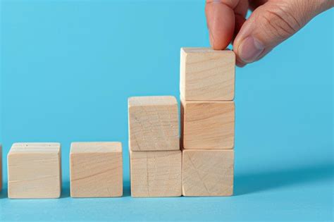 Hand Arranging Wood Cubes As Stairs On Blue Background Premium Ai
