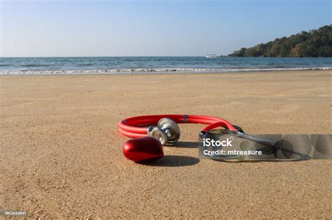 모델의 이미지 햇볕이 잘 드는 모래 해변 썰물 때 부서지는 파도 바다와 해안선 스트레스없는 건강과 웰빙 개념 전경에 초점 복사 공간에 청진기로 플라스틱 빨간 심장 0명에