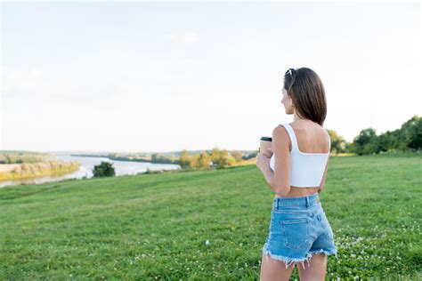 강가의 여름 공원에서 여자는 커피와 차 한 잔을 손에 들고 거리를 바라보며 아름다운 전망과 풍경을 즐깁니다 텍스트 복사본을 위한