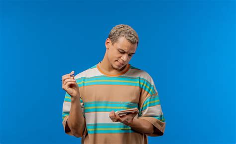 웃는 남자가 펜으로 플래너에 메모를 쓰고 있다 학생 남자는 주 월 연도의 노트북에 미래 계획과 할 일 목록을 씁니다 파란색 배경에 개인 일기를 유지합니다 계획에 대한 스톡