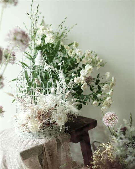 A Birdcage Filled With Flowers Sitting On Top Of A Table