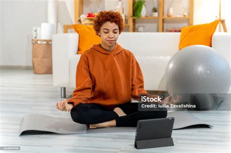 요가 마음 챙김 명상 집에서 요가를 연습하는 젊은 건강한 아프리카 소녀 연꽃에 앉아 있는 여자는 실내에서 편안한 미소를 짓고 명상하는 요가 매트에 앉아 있다 집에서 호흡