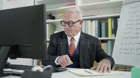 Senior Teacher Using Computer Taking Notes At University Classroom