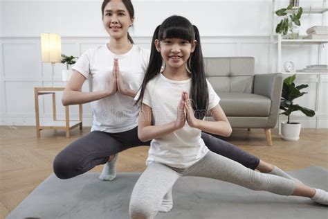 Asian Thai Mother And Daughter Practice Yoga On Living Room Floor