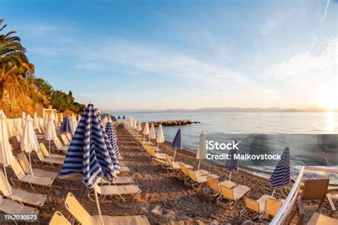 해안 코르푸 섬 그리스의 여름 일출 그리스 산 본토의 완벽 한 경관을 자랑 하는 선베드와 파라솔이 비치 되어 있습니다 코르푸에