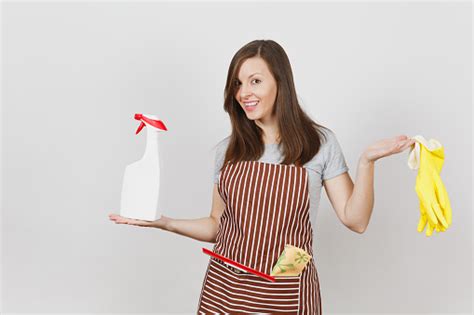 흰색 배경에 고립 된 포켓 고무 롤러 걸 레 청소와 줄무늬 앞치마에 젊은 미소 주부 가 정부 여자 청소기 액체 노란색 장갑과 스프레이 병을 들고 병 복사 공간입니다 가사