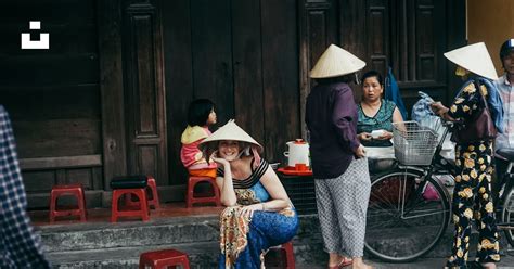 파란색과 흰색 드레스를 입은 여자가 의자에 앉아 있습니다 사진 Unsplash의 무료 호이안 이미지