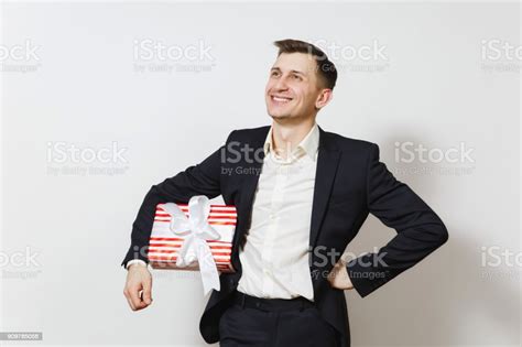 양복 선물 흰색 배경에 고립 된 빨간 선물 상자를 들고 젊은 잘생긴 웃는 남자 광고에 대 한 공간을 복사 합니다 성 발렌타인의