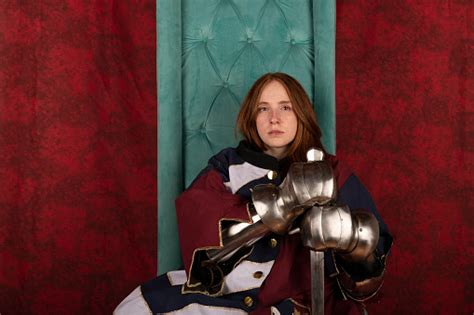 중세의 역사 갑옷을 입은 아름다운 중세 기사가 붉은 배경에 왕좌에 앉아 있는 초상화 기사 사람의 역할에 대한 스톡 사진 및 기타 이미지 기사 사람의 역할 가공의 인물