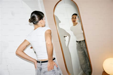 A Woman Standing In Front Of A Large Mirror Photo Fashion Image On