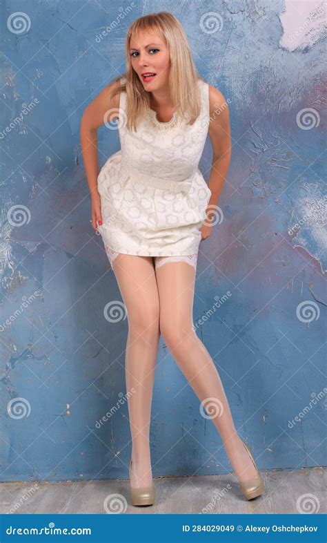 Beautiful Blonde Girl With Long Legs In White Stockings And High Heels