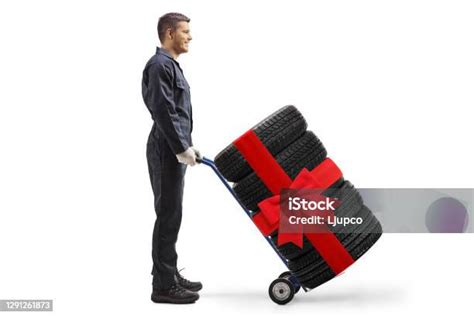 흰색 배경에 고립 된 손 트럭에 빨간 활으로 자동차 타이어를 밀고 있는 정비사 노동자의 전체 길이 프로필 샷 바퀴에 대한 스톡 사진 및 기타 이미지 Istock