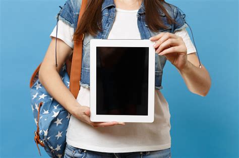 파란색 배경에 고립 된 빈 검은색 빈 화면으로 태블릿 Pc 컴퓨터를 들고 배낭 데님 옷에서 젊은 여자 학생을 잘립니다 고등학교에서 교육입니다 광고에 대 한 공간을 복사
