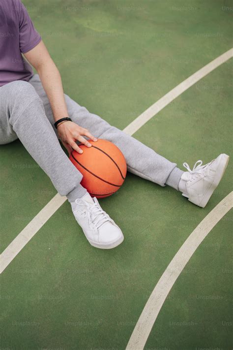 농구공을 들고 코트에 앉아 있는 사람 사진 Unsplash의 야외 스포츠 이미지