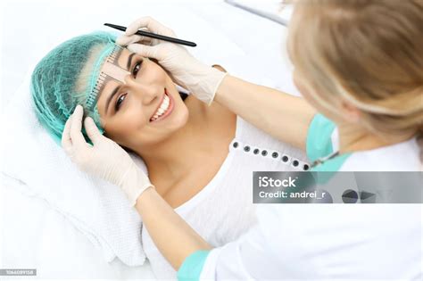 전문 미용사 화장품 눈금자를 사용 하 여 여자 얼굴에서 눈 썹 라인을 수정 하려고 합니다 뷰티 살롱 근접 촬영에서에서 영구이 마 메이크업입니다 미용 치료 건강관리와 의술에