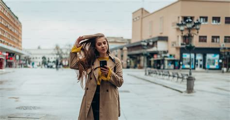 도시에서 산책하는 동안 스마트폰을 사용하는 젊은 아름다운 여자 사진 Unsplash의 유행 이미지