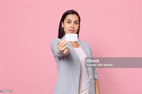 스튜디오에서 분홍색 파스텔 벽 배경에 고립 된 신용 은행 카드를 들고 줄무늬 재킷에 아름 다운 멋진 젊은 여자의 초상화 사람들은 진심으로 감정 라이프 스타일 개념입니다 복사