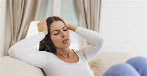 두통으로 집에서 소파에 앉아 고통을 느끼고 몸이 좋지 않은 표정으로 매력적인 여성의 초상화 화가 우울한 여자는 소파에 누워 강한 두통 편두통을 느낀다 사진