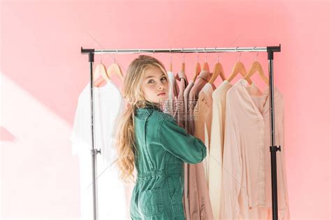 穿着时装服在衣架上选择衣服的有高清图片下载 正版图片503503277 摄图网