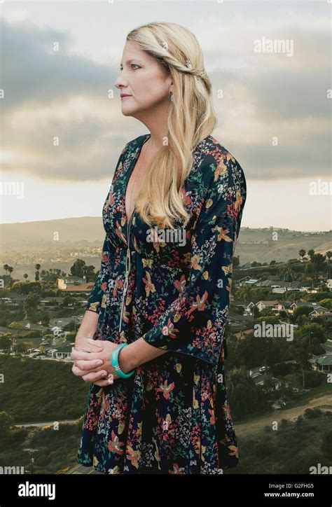 Portrait Of Woman With Long Blonde Hair Against Neighborhood Landscape