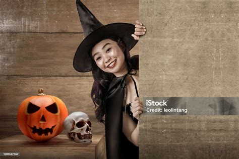 나무 벽 배경이있는 빈 보드를 들고 서있는 모자를 쓴 아시아 마녀 여성 검은색에 대한 스톡 사진 및 기타 이미지 검은색 공란 공포 무서움 Istock