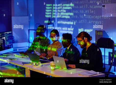 Several Young Contemporary Software Developers Sitting In Row By Desks During Presentation Of