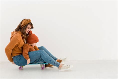 Вид сбоку мама с маленьким мальчиком на скейтборде Бесплатно Фото