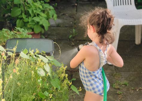 Beautiful Girl In A Bathing Suit Is Watering Plants On A Summer Day