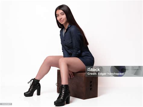 검은 머리카락과 짧은 치마를 입은 라티나 소녀는 흰색 배경에 고립 된 사과 상자에 앉아 있습니다 갈색 머리에 대한 스톡 사진 및 기타 이미지 Istock