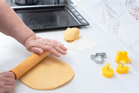 노인 여성은 하얀 부엌에 롤링 핀으로 쿠키를위한 반죽을 굴려 나간다 선택적 초점 행복한 부활절 개념 쿠키 제작 과정 집에서 요리