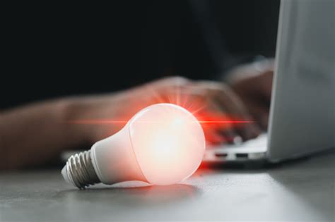 남자들은 책상 위에 전구로 일하는 컴퓨터를 사용하고 책상에서 일하고 창의성과 혁신은 성공의 열쇠입니다 개념에 대한 스톡 사진 및