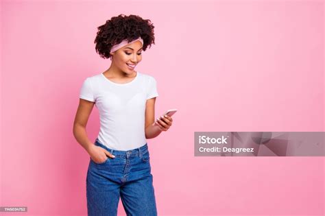 핑크 파스텔 배경 위에 고립 된 새로운 장치 가젯을 사용 하 여 멋진 매력적인 귀여운 매력적인 윈 섬 여성 매혹적인 사랑 스러운 자신감 쾌활 한 곱슬 머리 소녀의 초상화