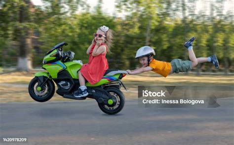 아이들은 어린이 전기 자동차를 타고 공원에 타고 소년이 오토바이 좌석을 잡고 공중에서 날아 다니는 만화 음모가 소녀를 놀라게합니다 아이에 대한 스톡 사진 및 기타 이미지