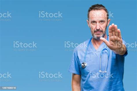 중 년 노인의 수석 의사 남자 중지 하 고 격리 된 배경 위에 의료 유니폼을 입고 노래 손바닥으로 얼굴에 부정적이 고 심각한 제스처와 경고 식입니다 의사에 대한 스톡 사진