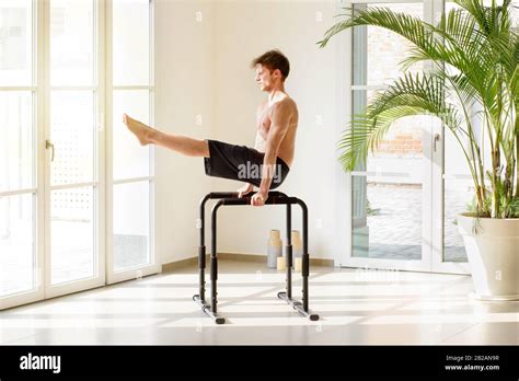 Fit Young Man Working Out On Parallel Bars Doing V Sit Exercises During