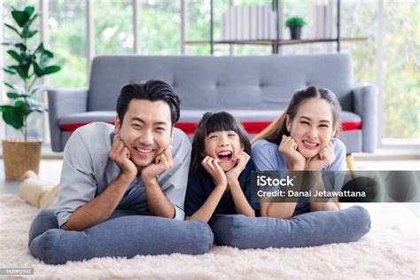 젊은 가족 아시아 아버지 어머니와 아이 딸은 집에서 양질의 시간을 보내는 바닥에서 휴식을 취하고 누워 있습니다 집에서 엄마와 함께 행복하게 웃고있는 더 먼 뒤에 앉아있는
