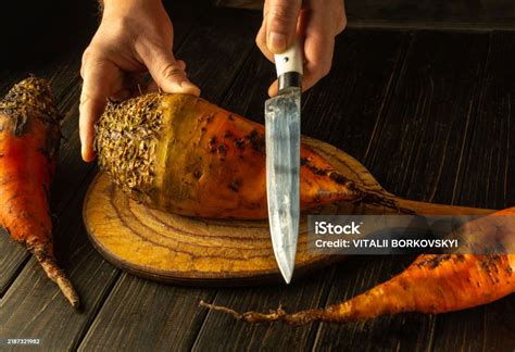 손으로 생생한 비트 뿌리 채소를 나무 도마에 솜씨 있게 썰어 놓습니다 주방의 따뜻한 색조는 요리의 창의성을 위한 매력적인 분위기를 조성합니다 건강한 생활방식에 대한 스톡