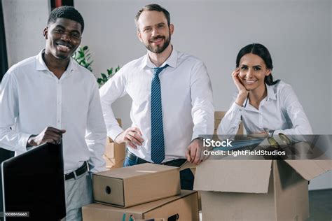 새로운 사무실에서 골 판지 상자를 풀고 하는 동안 카메라에 웃 고 행복 한 다민족 동료 경영자에 대한 스톡 사진 및 기타 이미지 경영자 기업 비즈니스 남자 Istock