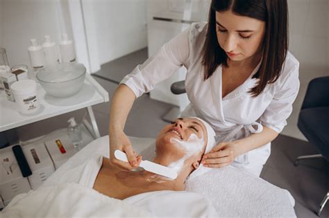 스파 살롱에서 여성 환자를 위해 흰색 화장용 페이셜 마스크를 적용하는 미용사의 근접 촬영 주름 방지 미용 절차의 개념 마사지에