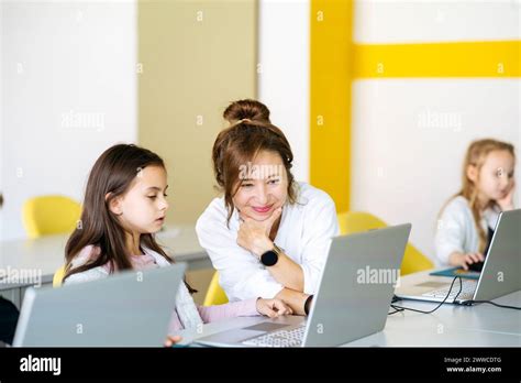 Smiling Teacher Teaching Computer Coding On Laptop To Girl In Classroom Stock Photo Alamy