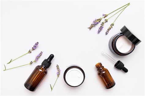흰색 배경에 라벤더 추출물이 함유 된 천연 유기농 화장품이 평평하게 놓여 있습니다 피펫이있는 유리 병 얼굴 크림 항아리 및
