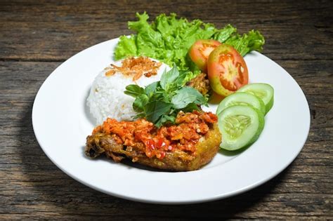 Ayam Geprek 인도네시아 음식 또는 삼발 핫 칠리 소스를 곁들인 Geprek 치킨은 흰색 접시에 밥을 제공했습니다