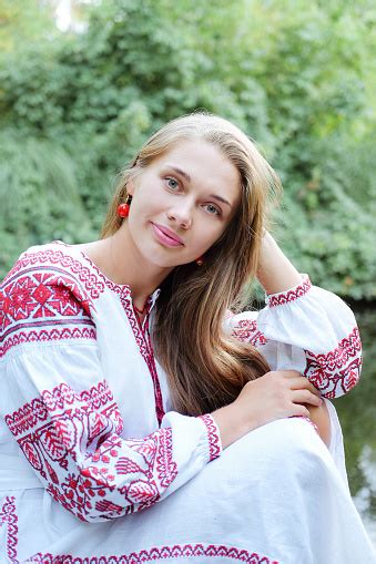 강 은행에서 기다리는 흰색과 빨간색 자 수 의상으로 긴 금발 머리와 파란 눈을 가진 아름 다운 슬라브 소녀 우크라이나어 지역의 전통 의상 강에 대한 스톡 사진 및 기타