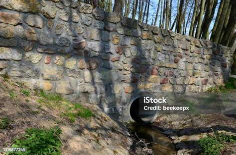 콘크리트 파이프에 의해 배수가있는 스트림 을 통해 작은 다리의 대규모 건설 난간은 낮은 직사각형 벽 모양의 석회암 돌로 만들어